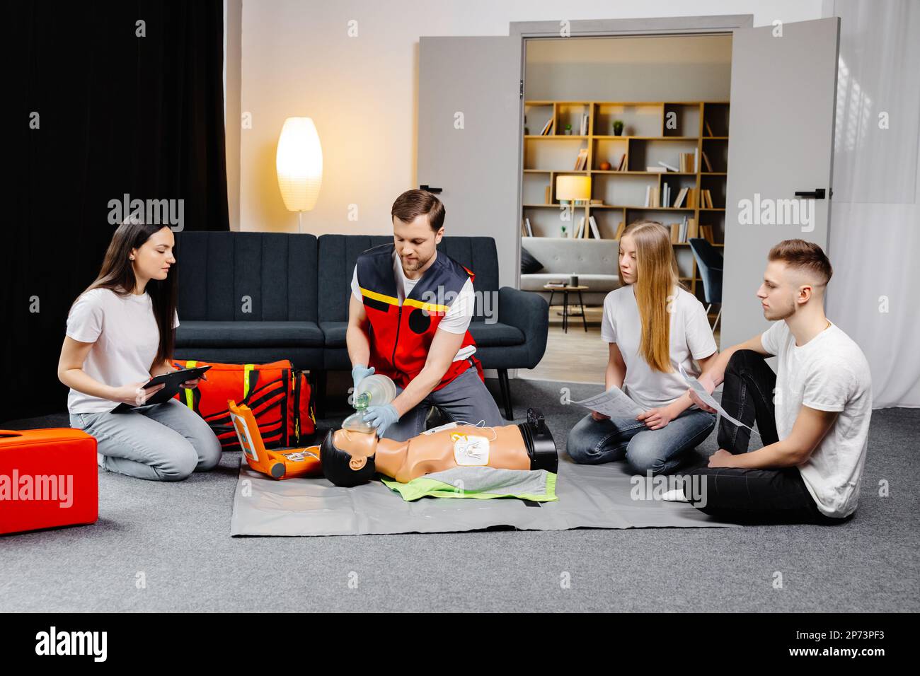 Young man instructor helping to make first aid heart compressions with ...
