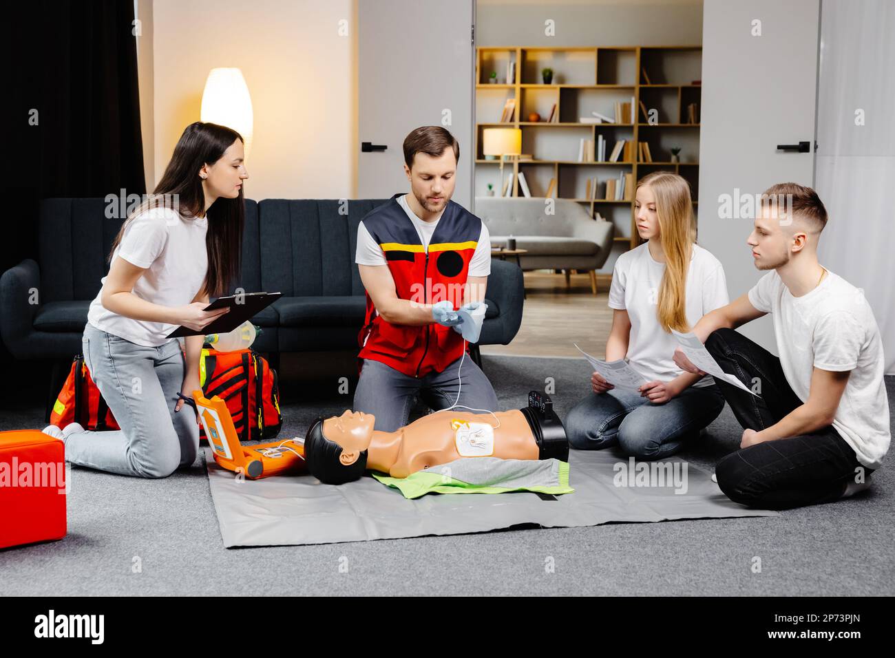 Young man instructor helping to make first aid heart compressions with ...