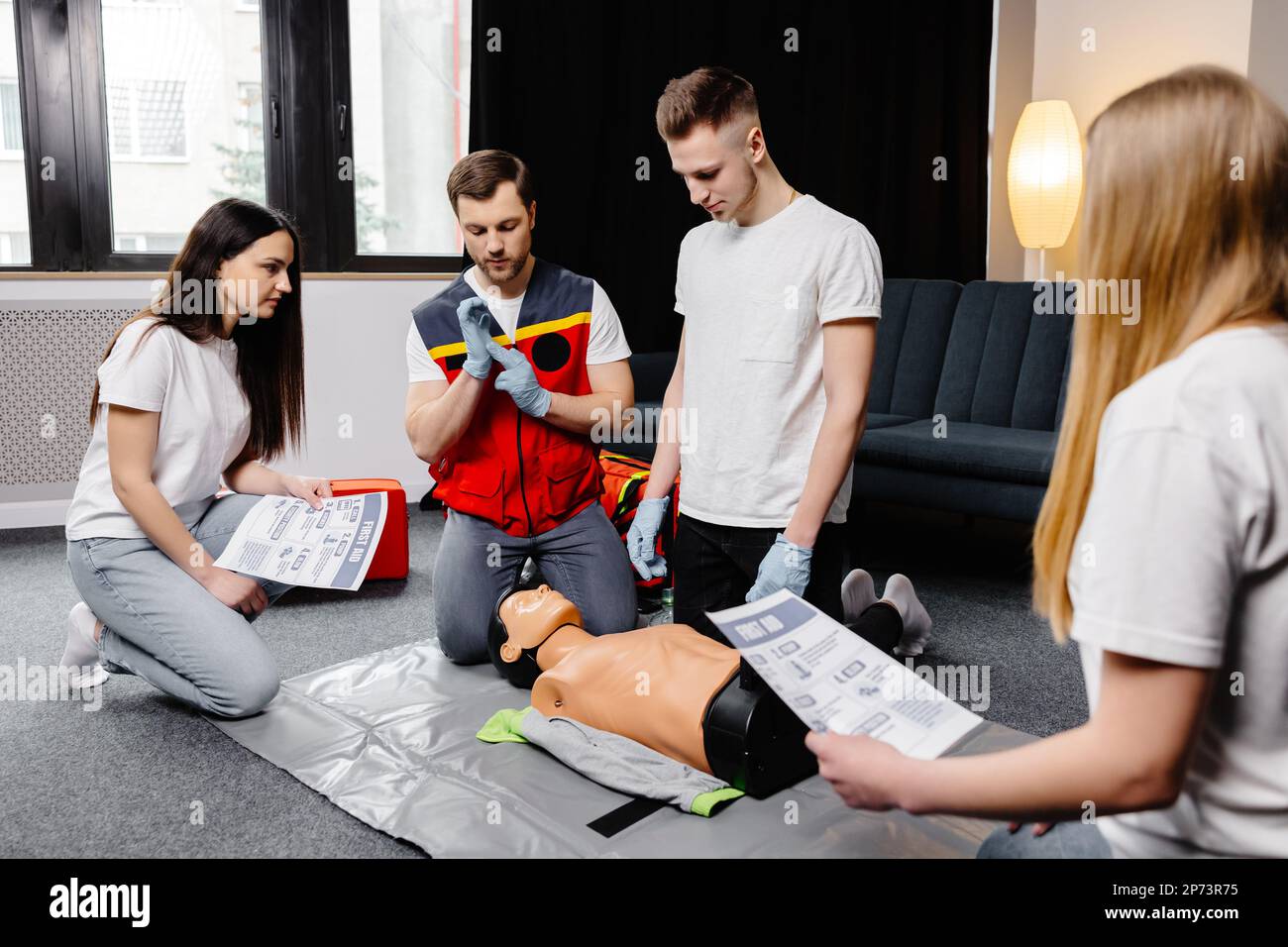 Young man instructor helping to make first aid heart compressions with ...