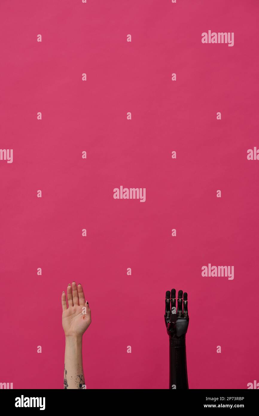 Close-up of girl with healthy hand and prosthetic hand against pink ...