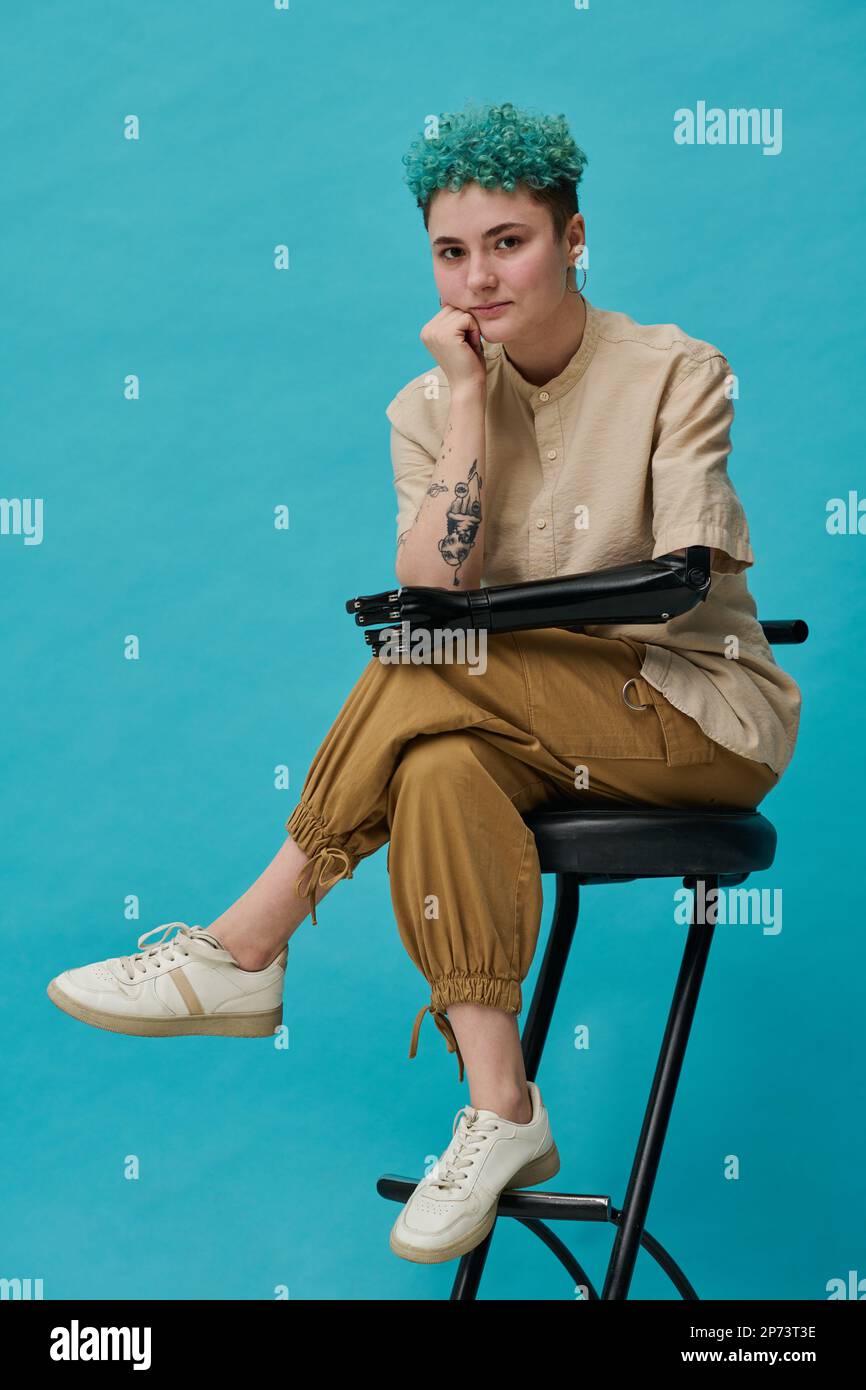 Portrait of teenage girl with prosthetic arm posing on chair against ...