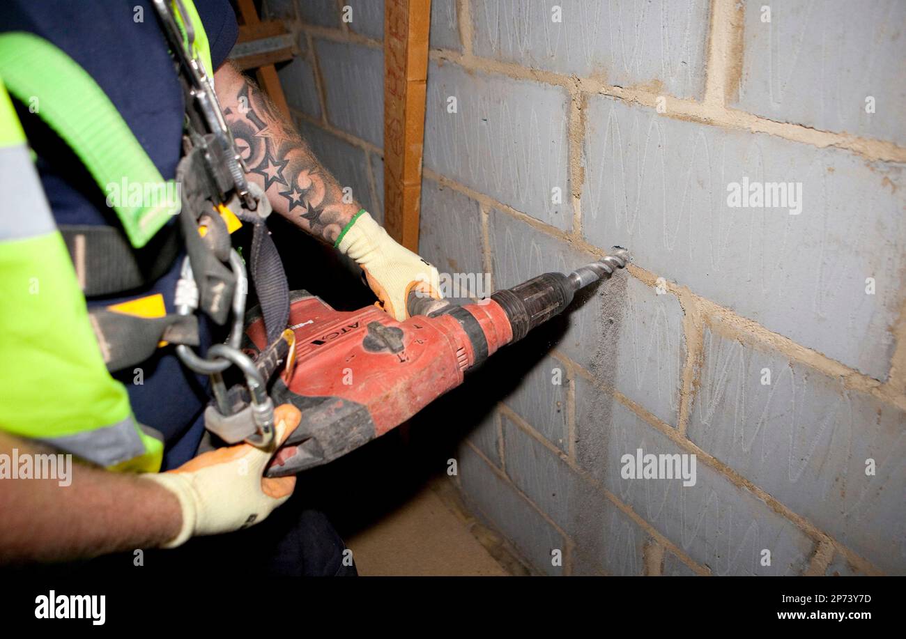 Illustrative image of cavity wall insulation. A worker from Total Insulation Solutions drills a ...
