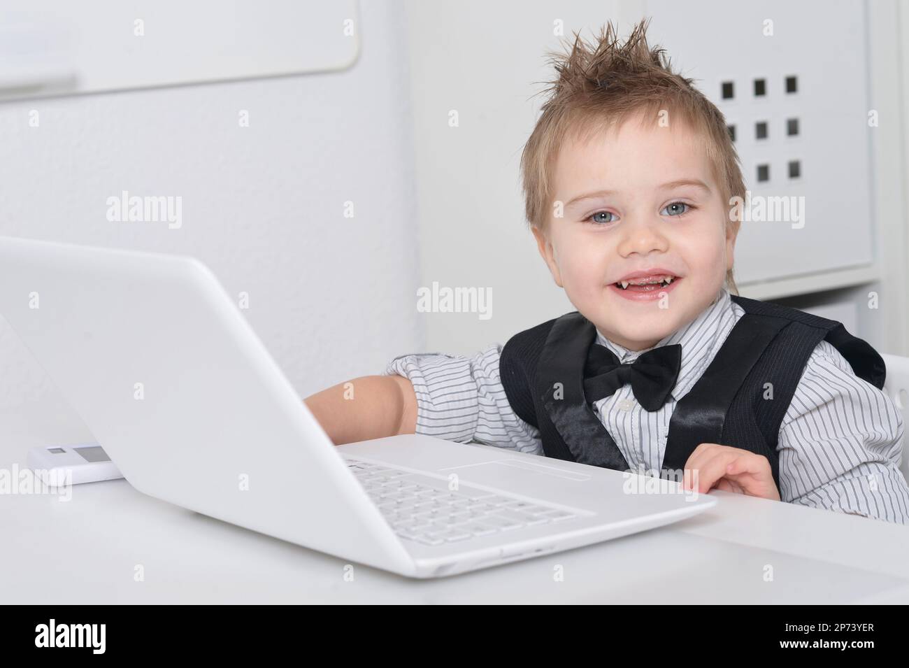 Little handsome boy sits with a computer Stock Photo - Alamy