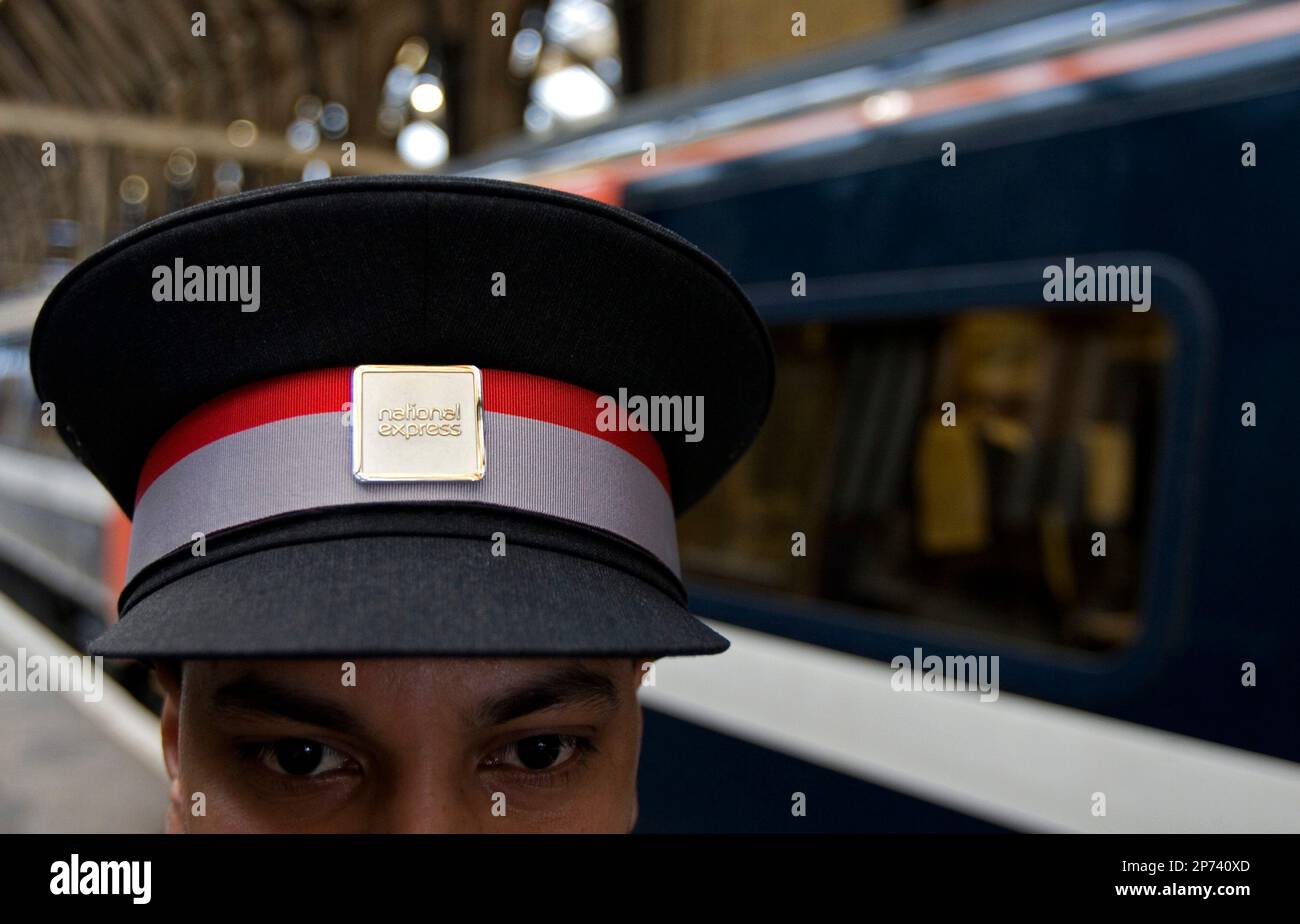A train guard signals beside a National Express train at Kings Cross ...