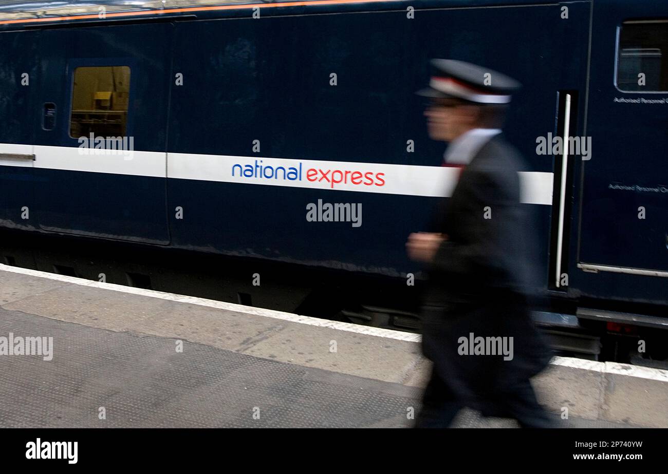 A train guard passes a National Express train at Kings Cross station ...