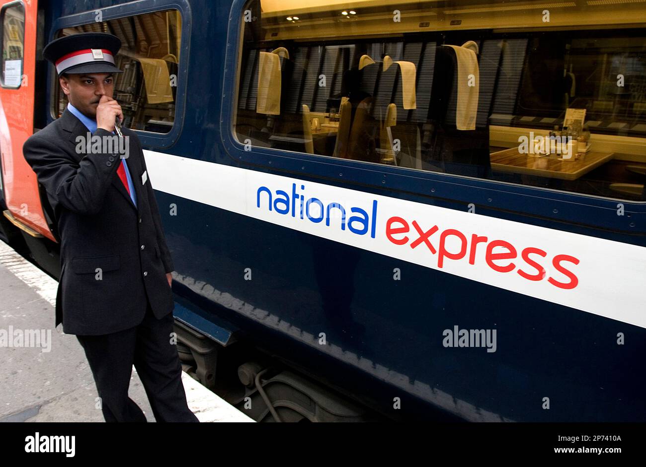 A train guard signals beside a National Express train at Kings Cross ...