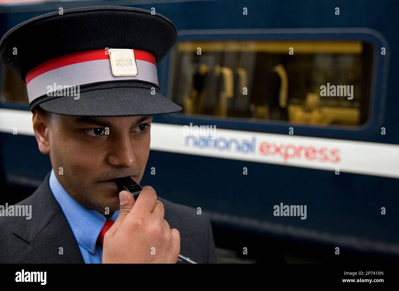 A train guard signals beside a National Express train at Kings Cross ...