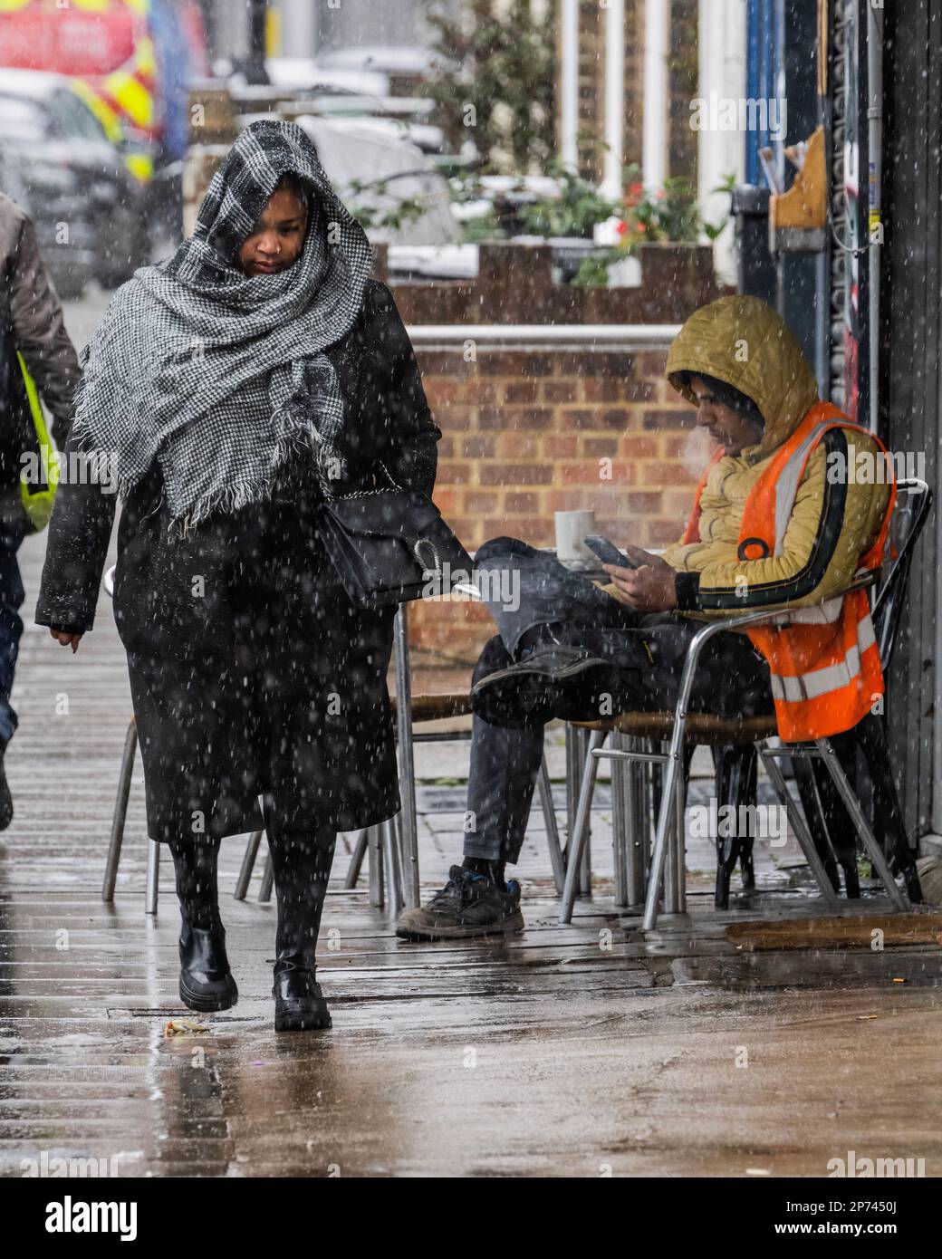 London, UK. 8th Mar, 2023. A man bravely sits outside with his coffee ...
