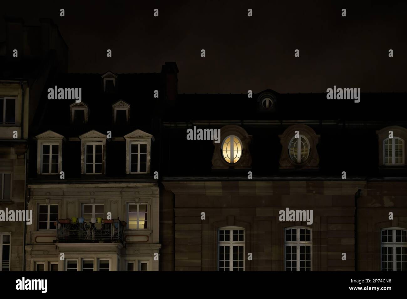 Luxury apartment building with only one oval window being illuminated ...