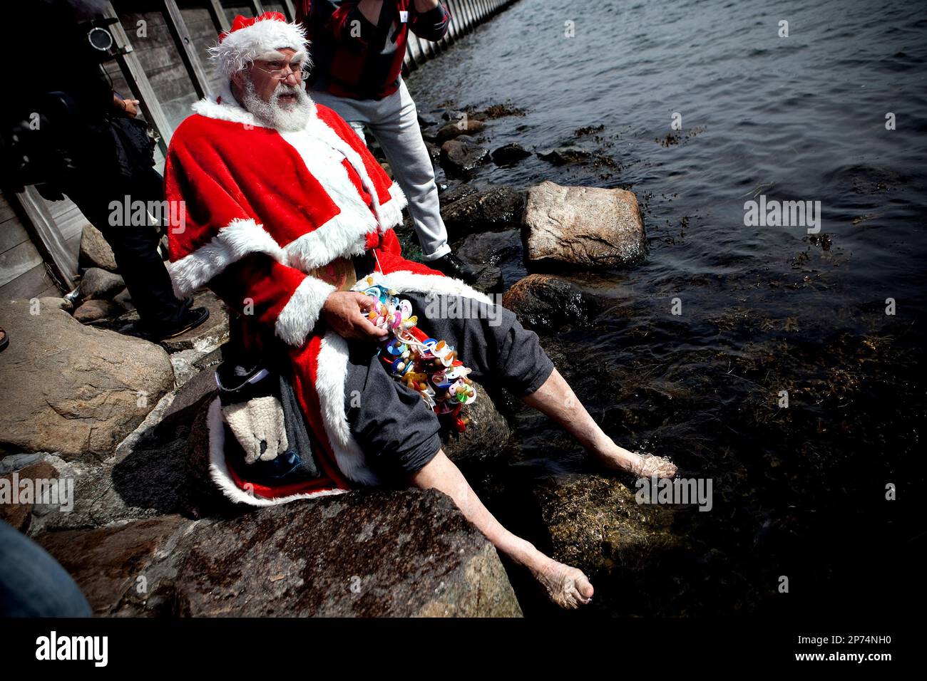 A Santa bathes his feet during the World Santa Claus Congress in front ...