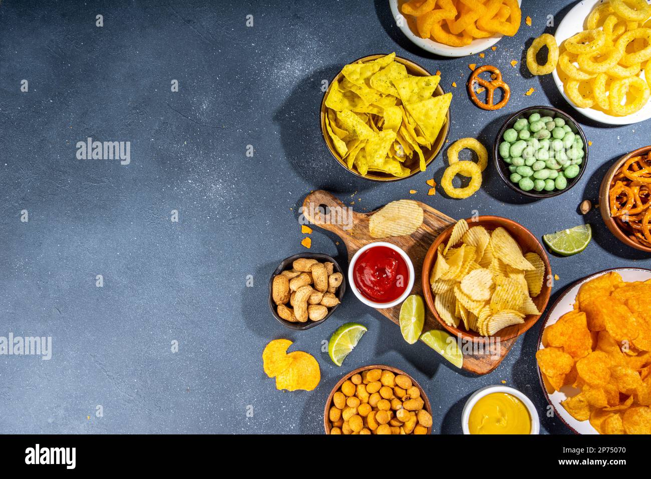 Various unhealthy salty bar snacks set. Dark grey table background with ...