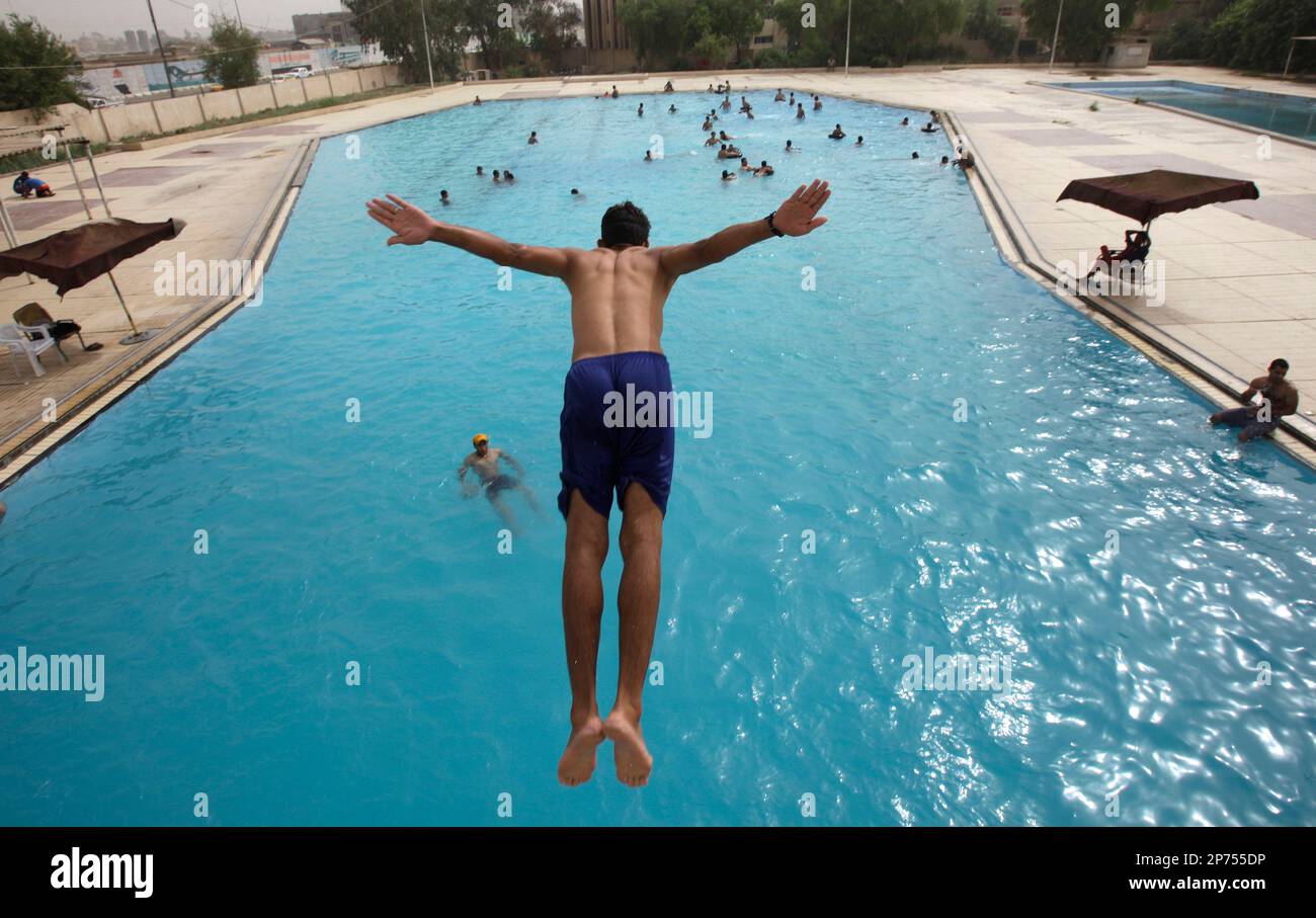 A man leaps into a public swimming pool in Baghdad, Iraq, Sunday, July ...