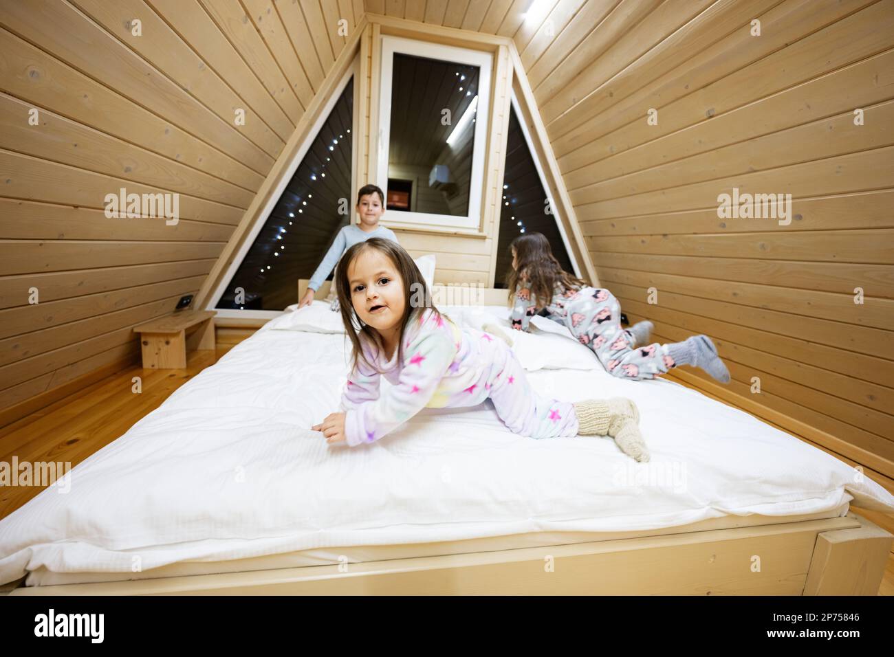 Children in soft warm pajamas playing at wooden cabin home. Concept of ...