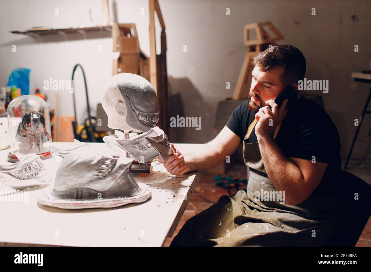 Artisan craftsman with mobile cell phone create mask based on plaster ...