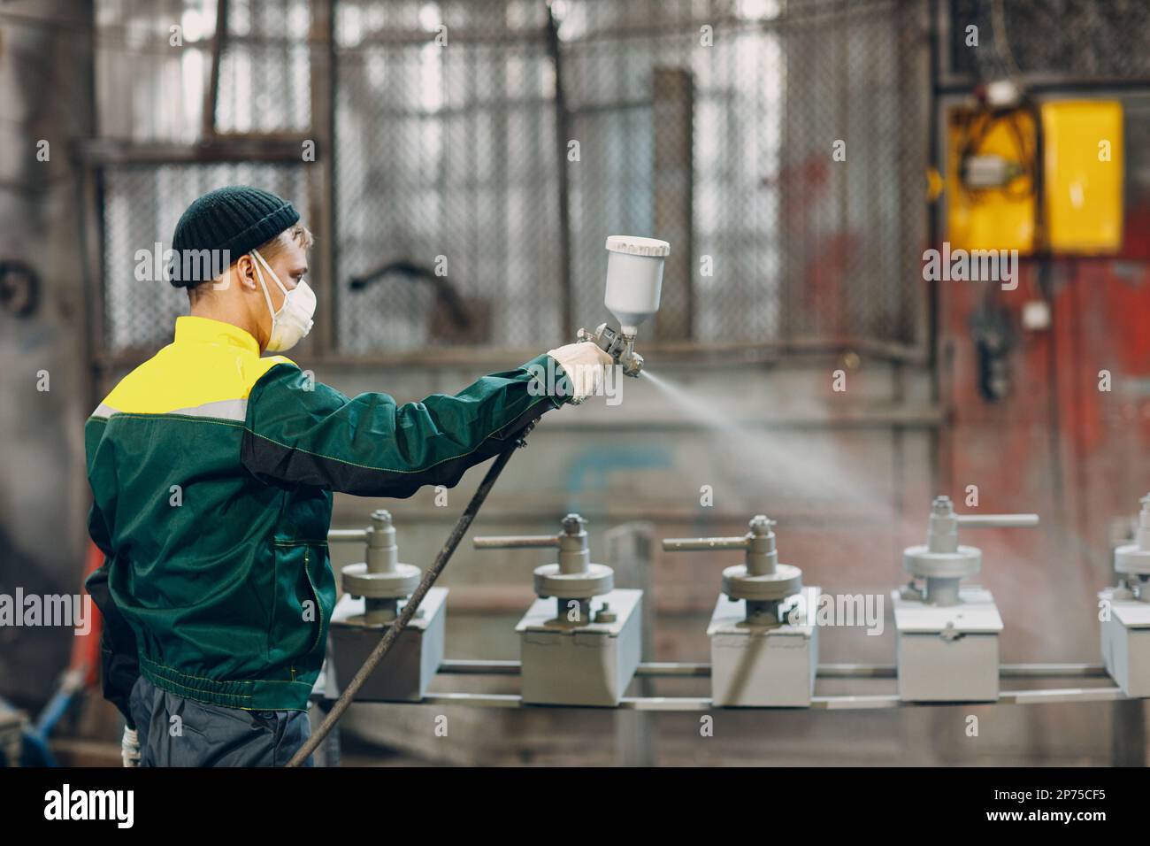 Powder primer coating of metal parts. Worker man in a protective suit ...