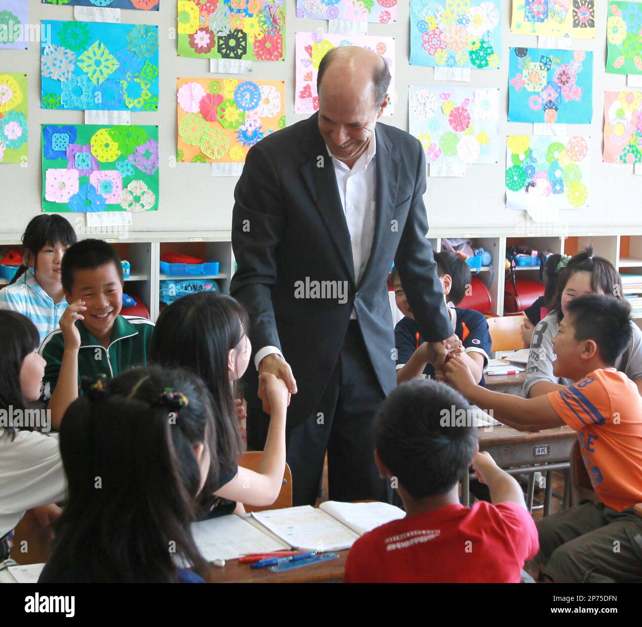 U.S. Ambassador to Japan John Roos (C) shakes hands with children of ...
