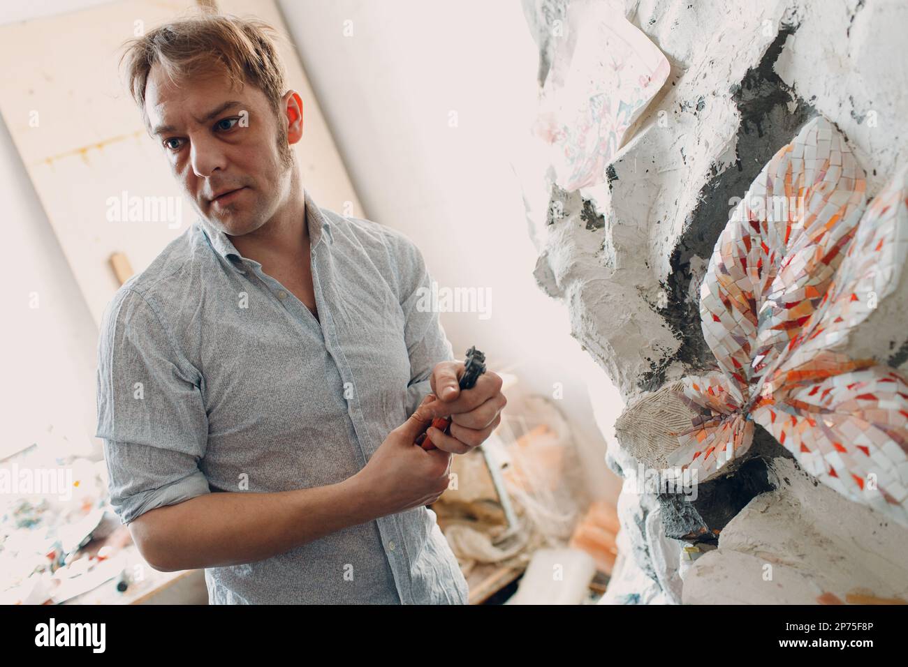 Workplace mosaics master making smalt glass mosaic panel. Man mosaicist ...