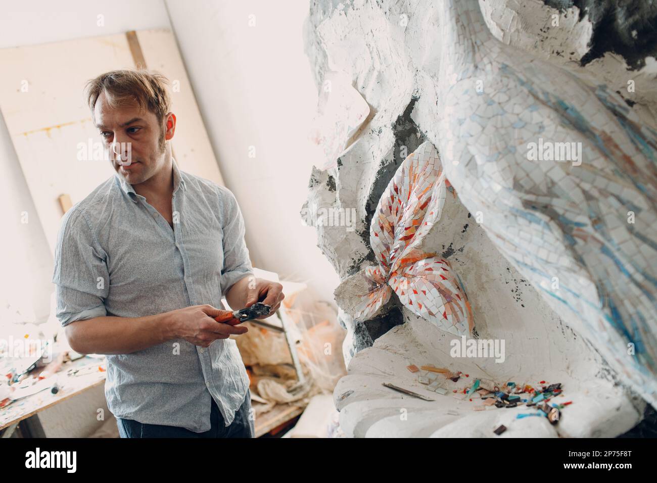 Workplace mosaics master making smalt glass mosaic panel. Man mosaicist ...