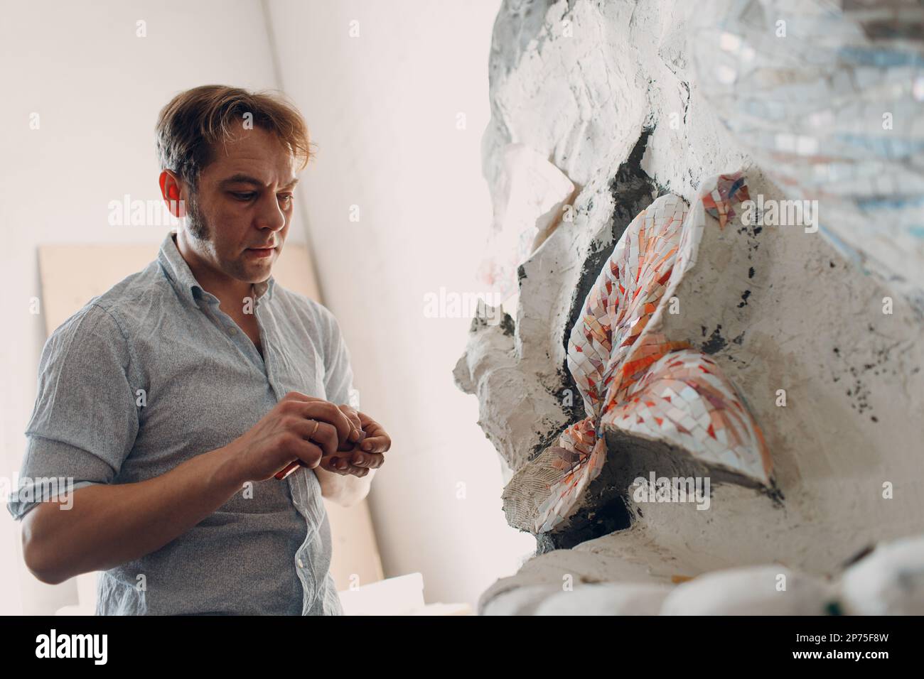 Workplace mosaics master making smalt glass mosaic panel. Man mosaicist ...