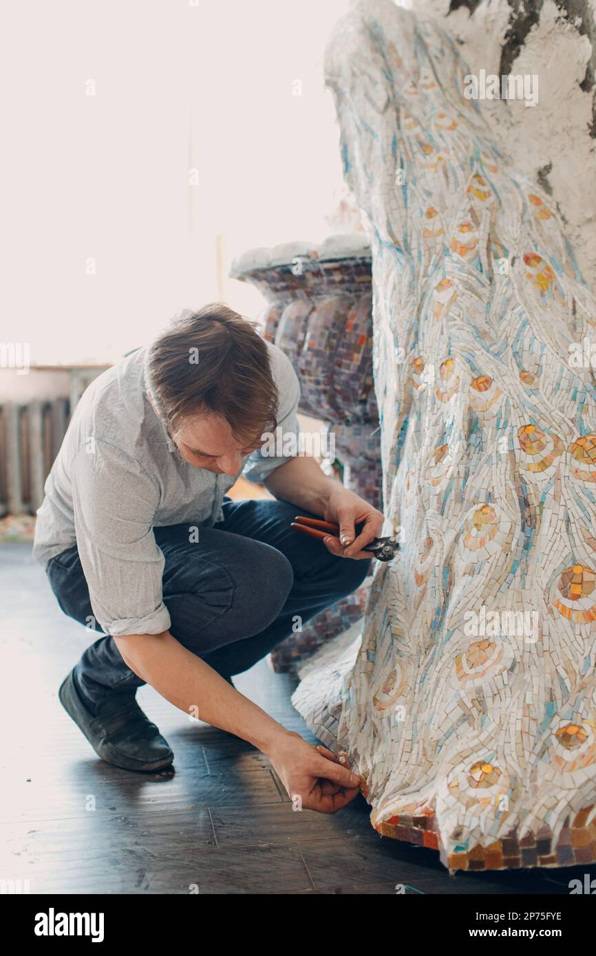 Workplace mosaics master making smalt glass mosaic panel. Man mosaicist ...