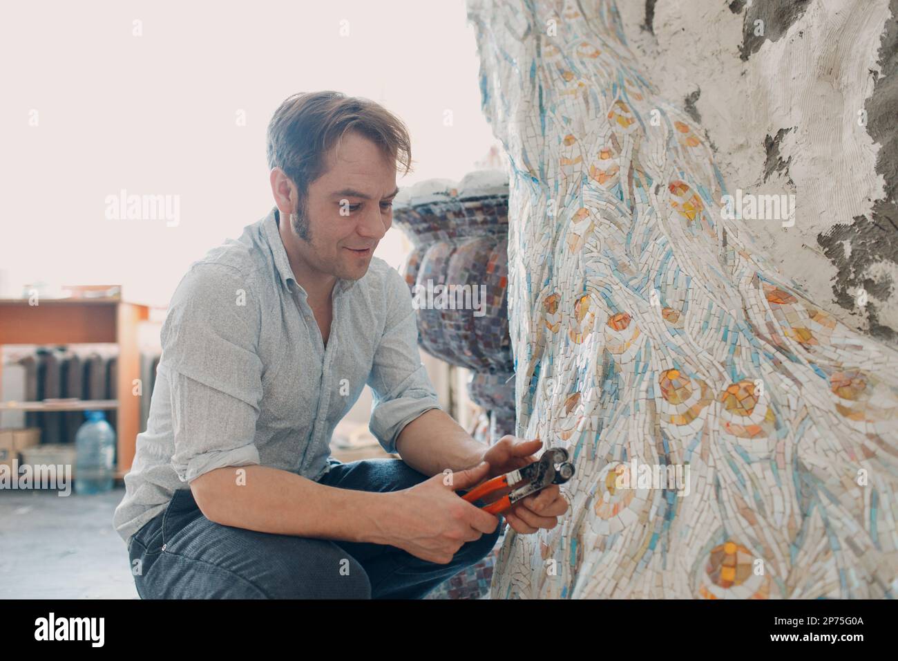 Workplace mosaics master making smalt glass mosaic panel. Man mosaicist ...