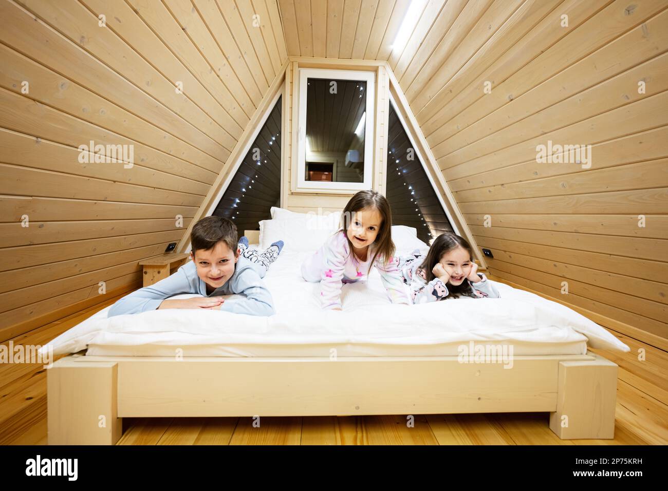 Children in soft warm pajamas playing at wooden cabin home. Concept of ...