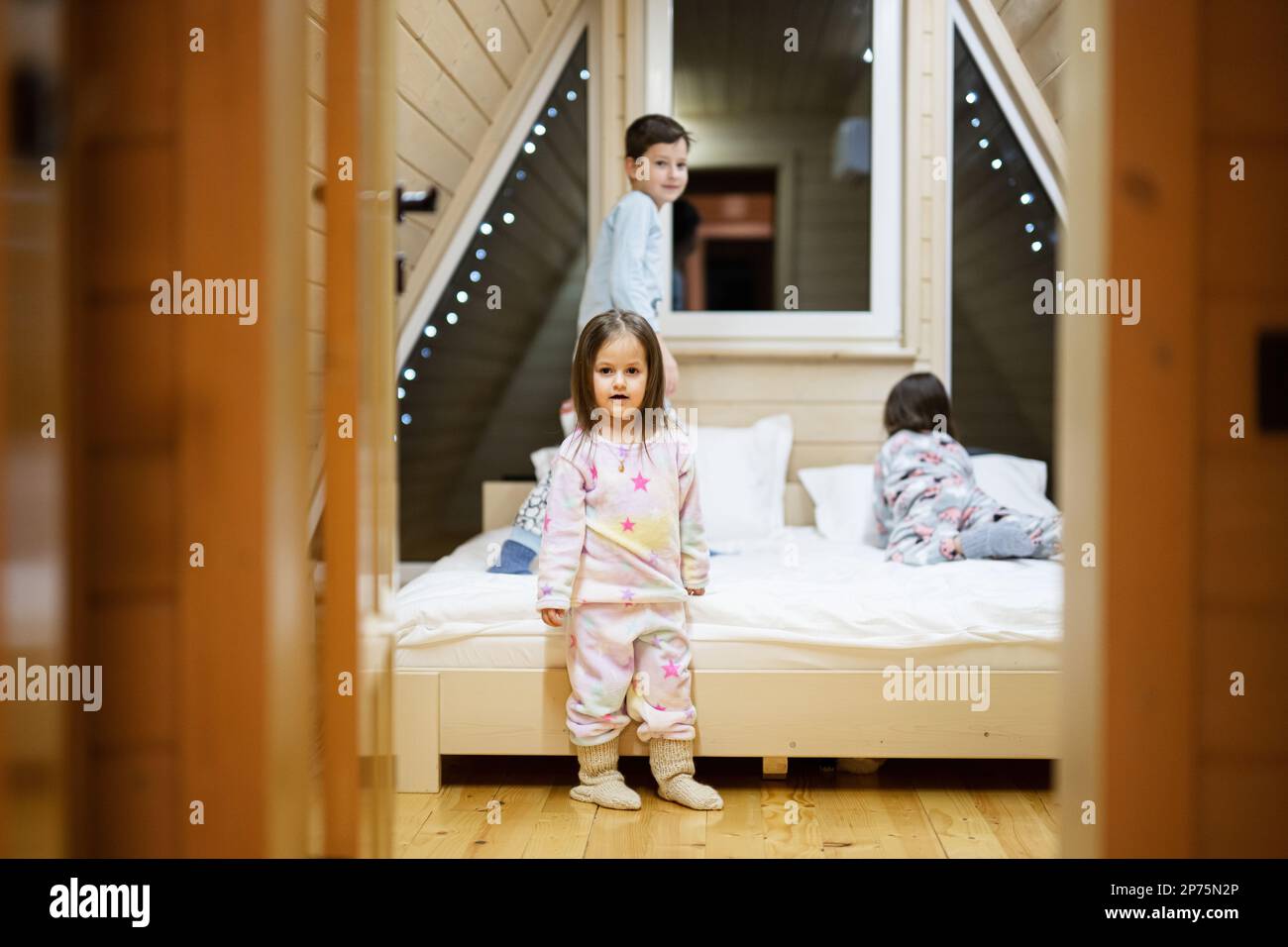 Children in soft warm pajamas playing at wooden cabin home. Concept of ...