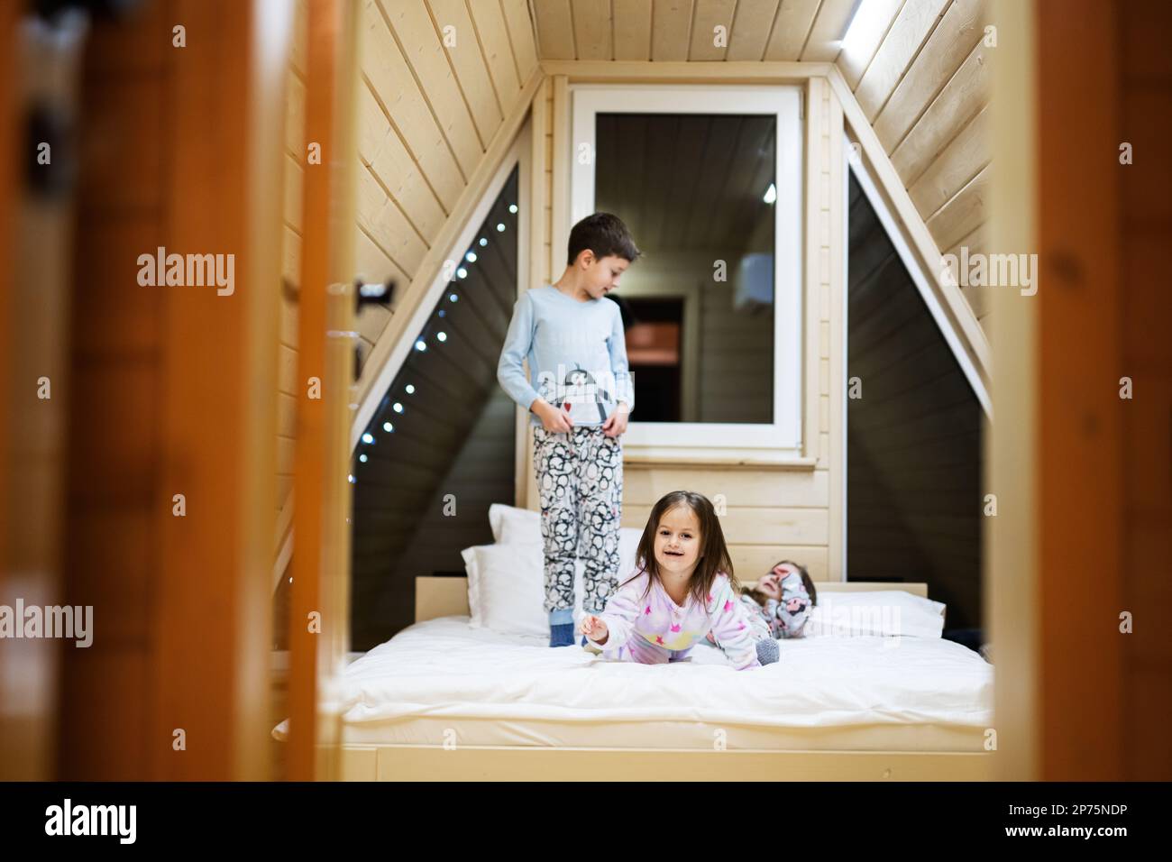 Children in soft warm pajamas playing at wooden cabin home. Concept of ...