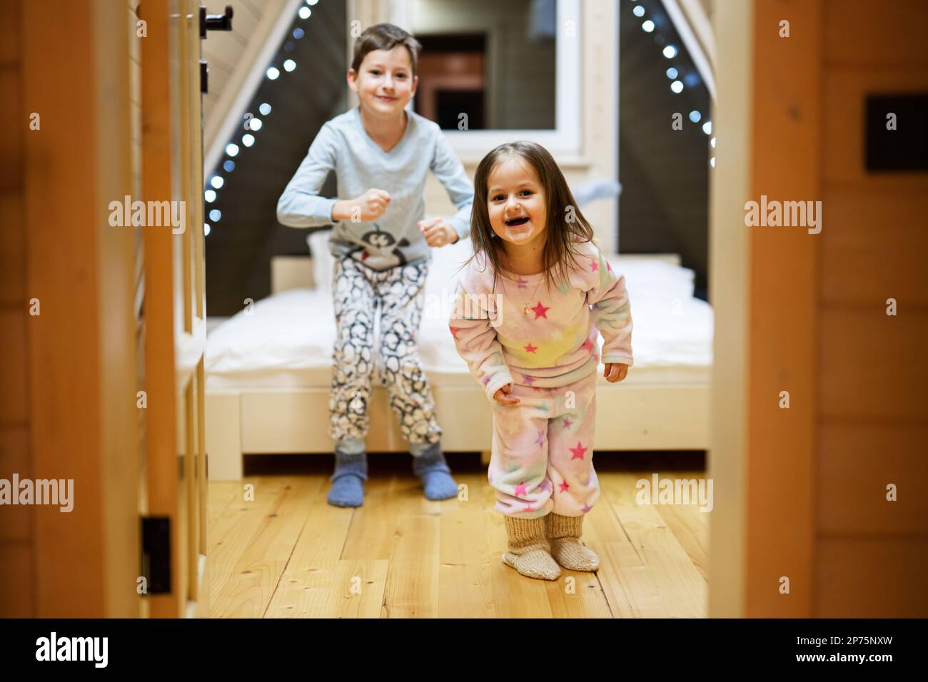 Children in soft warm pajamas playing at wooden cabin home. Concept of ...