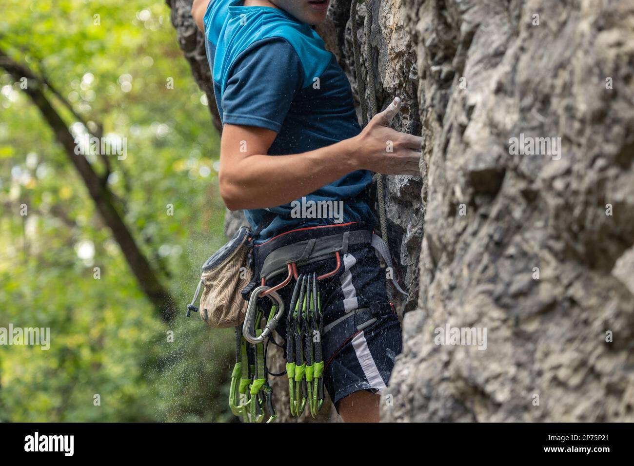 Male rock climber climbs on a rocky wall, while holding tight with ...