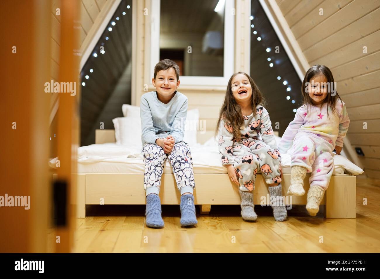 Children in soft warm pajamas playing at wooden cabin home. Concept of ...