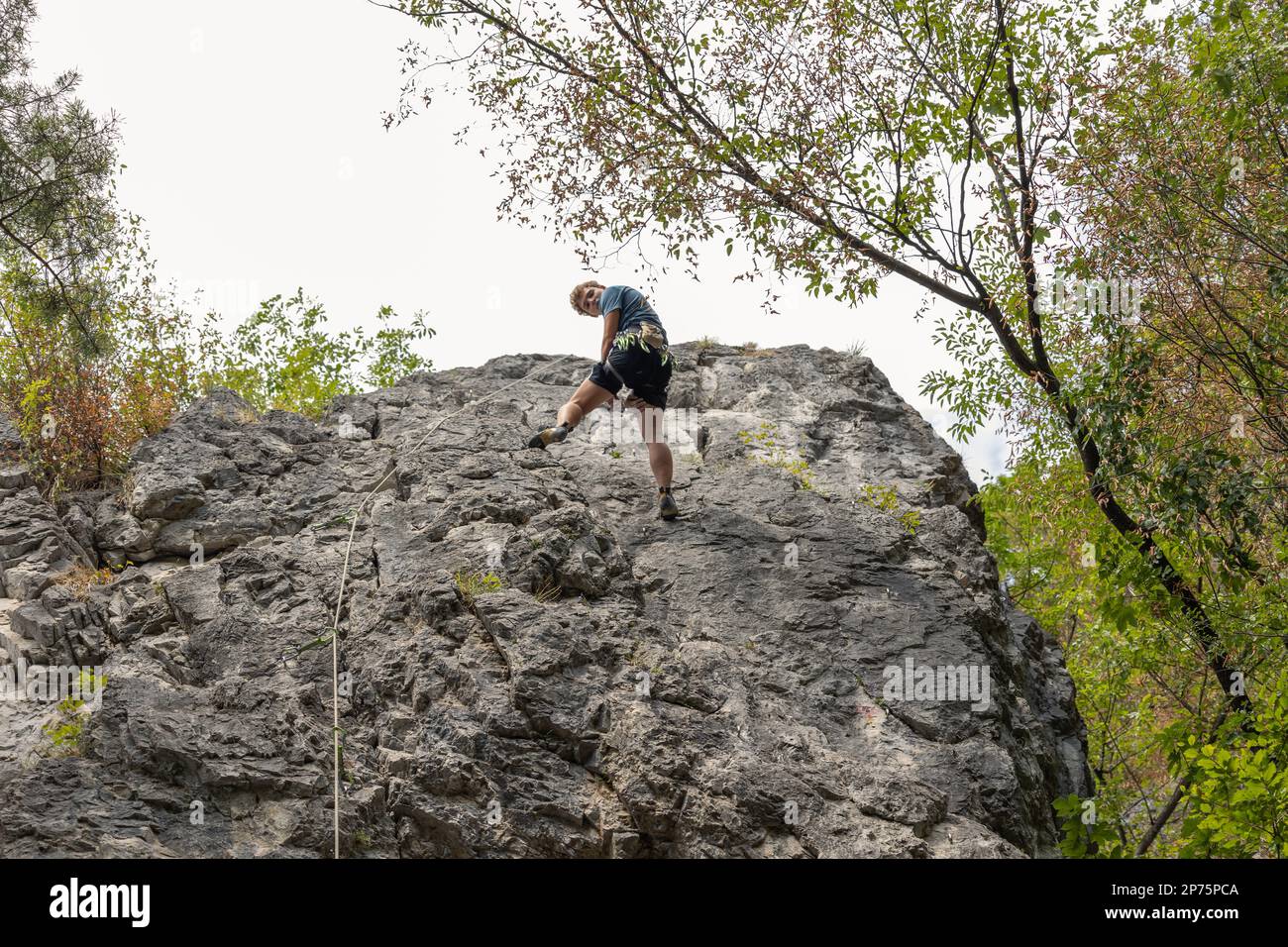 Wide shot od a male climber looking down and hanging on a rope while ...