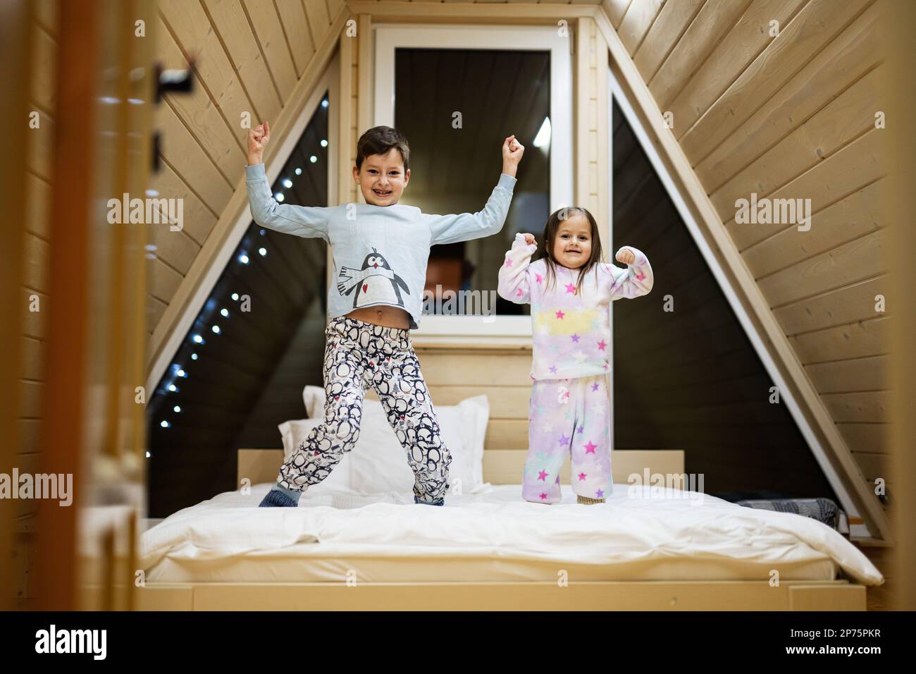 Children in soft warm pajamas playing at wooden cabin home. Concept of ...