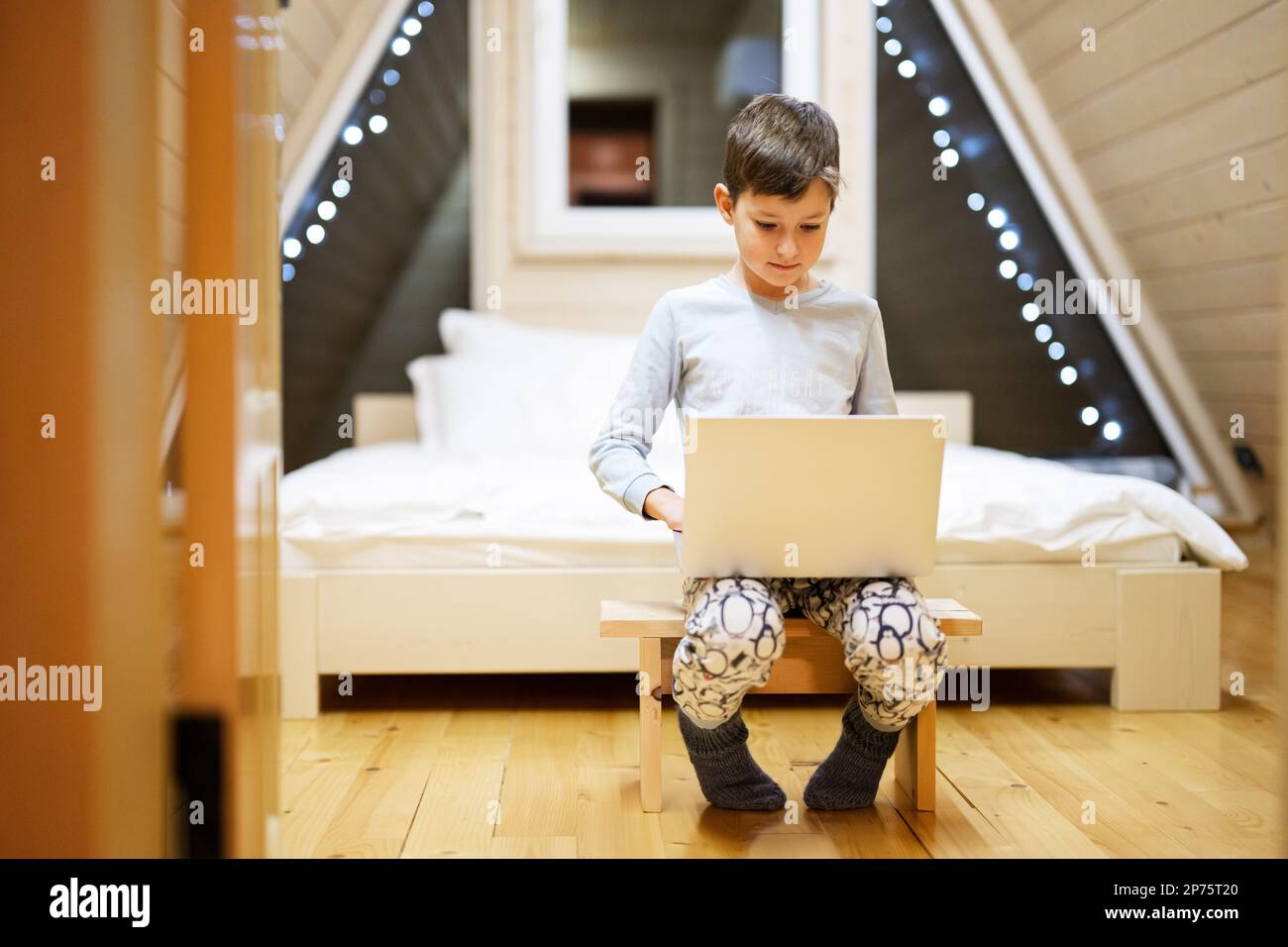 Boy in pajama sit with laptop at wooden cabin home. Concept of ...