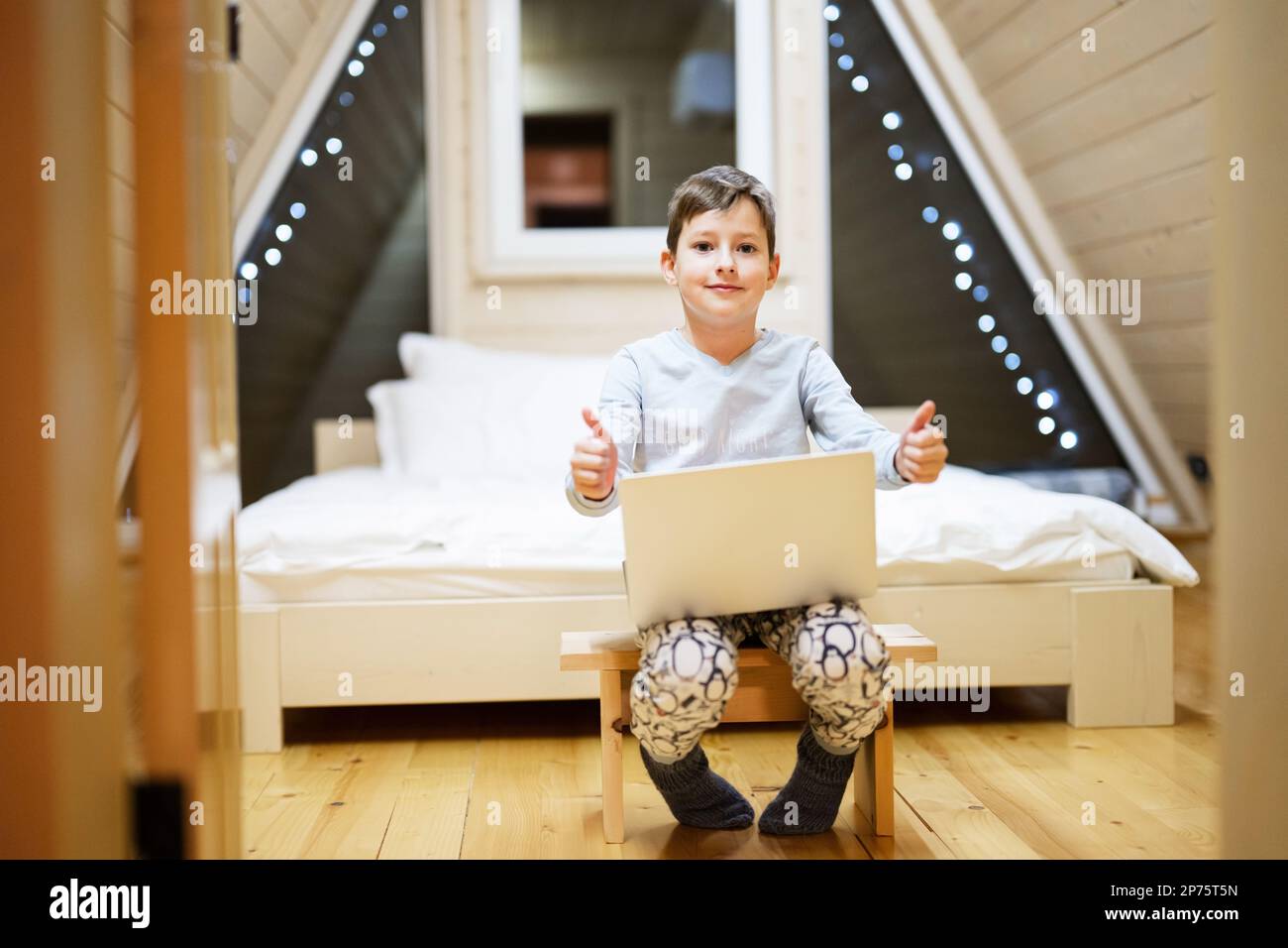 Boy in pajama sit with laptop at wooden cabin home. Concept of ...