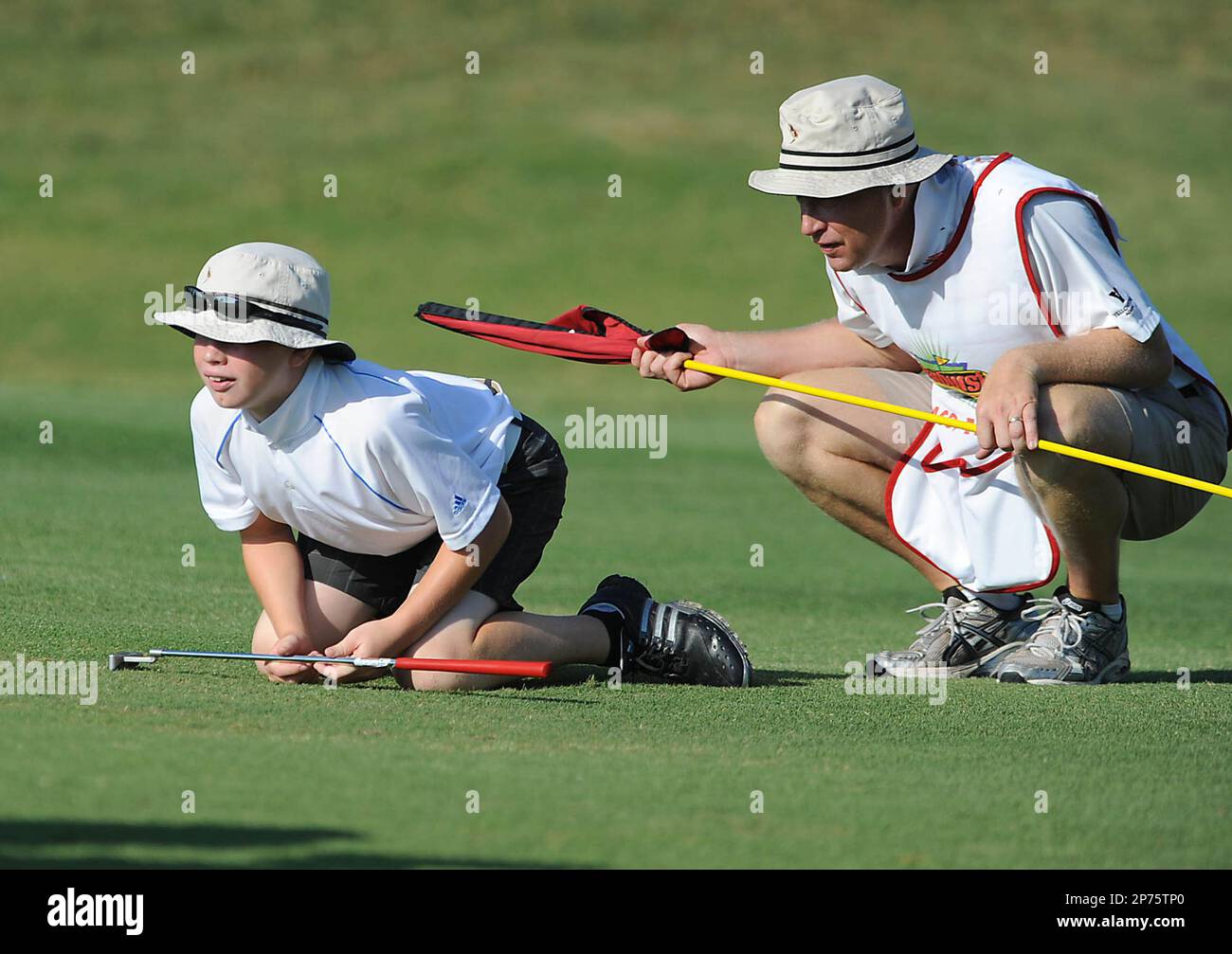 Travis Vick, left, 11, of Houston, eye's his putt with his dad and ...