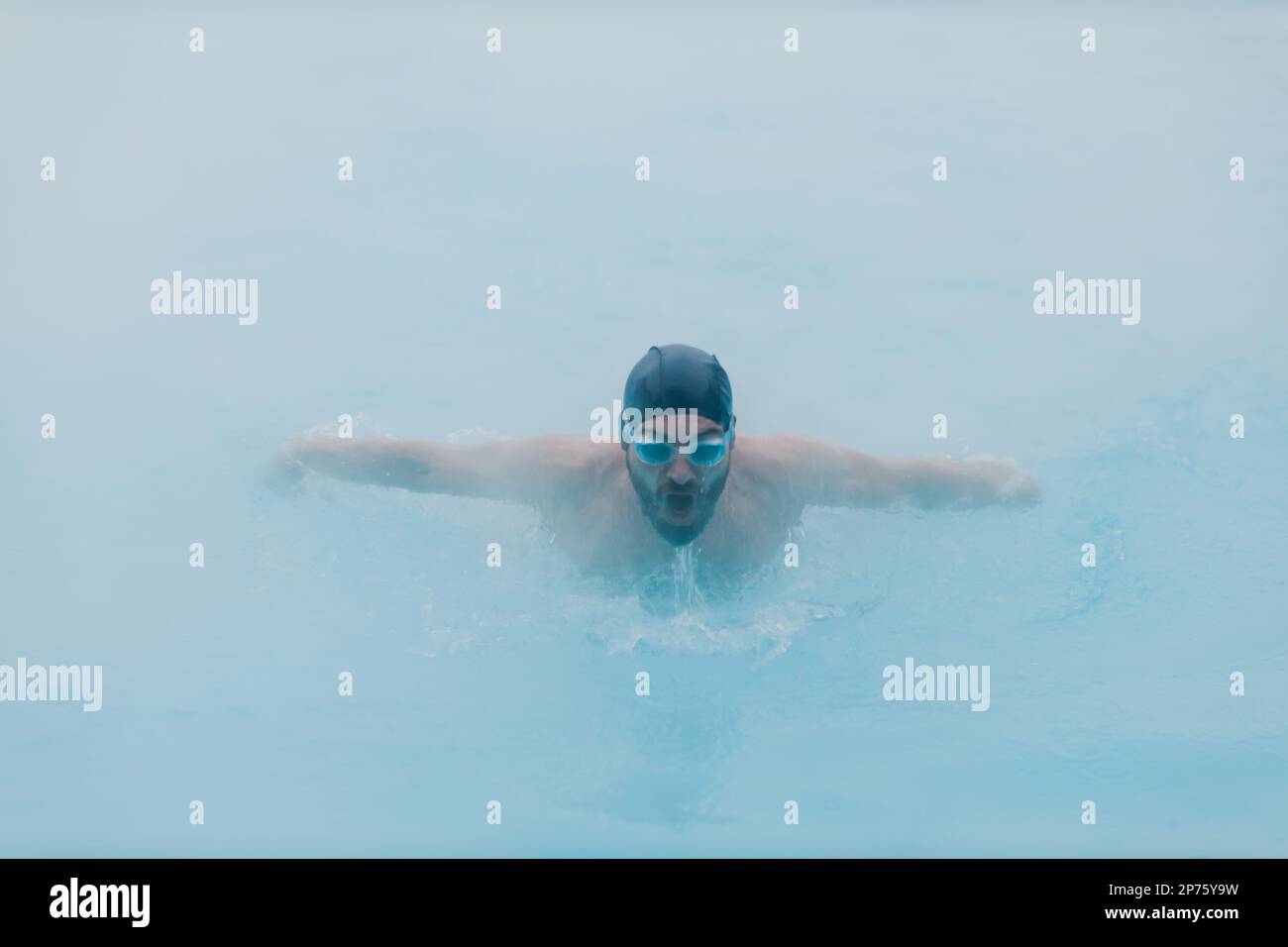 Fit swimmer male training swim butterfly stroke in open winter swimming ...