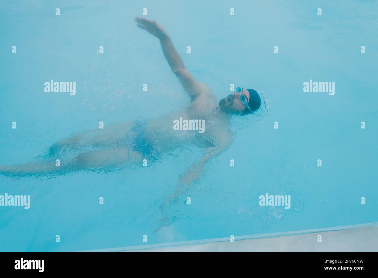 Fit swimmer male training swim backstroke in open winter swimming pool ...