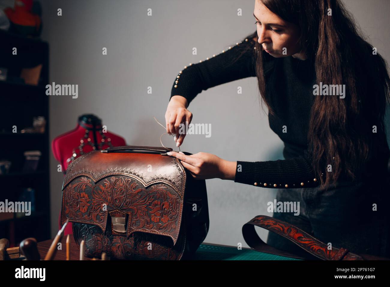 Tanner woman making sewing bag with pattern leather goods on workshop ...