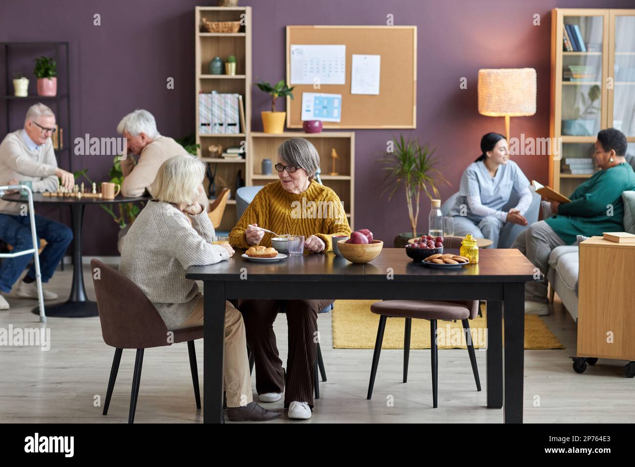 Full length view at common room in retirement home with diverse group ...