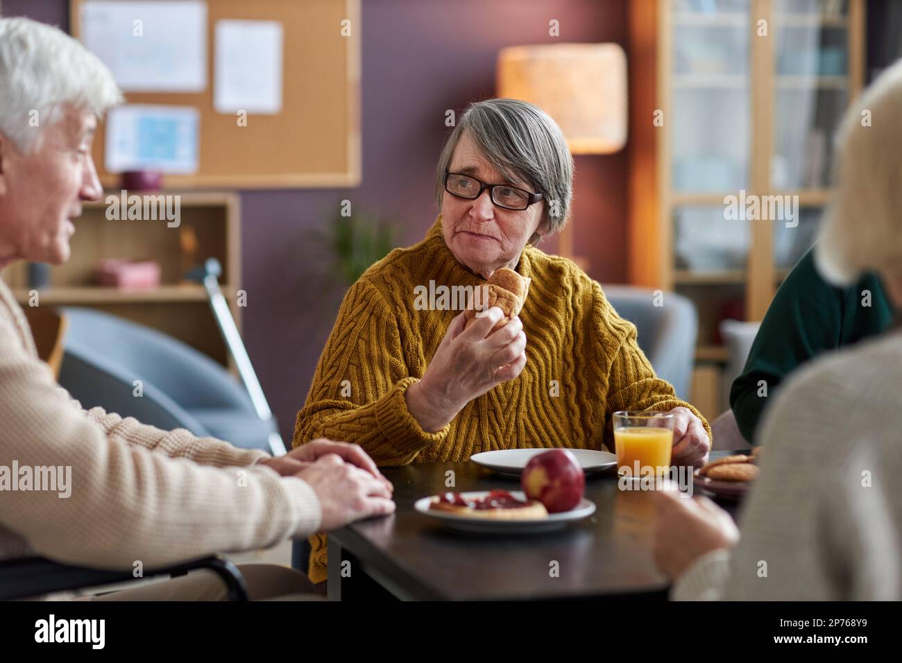 Group of seniors enjoying lunch at common table in retirement home ...