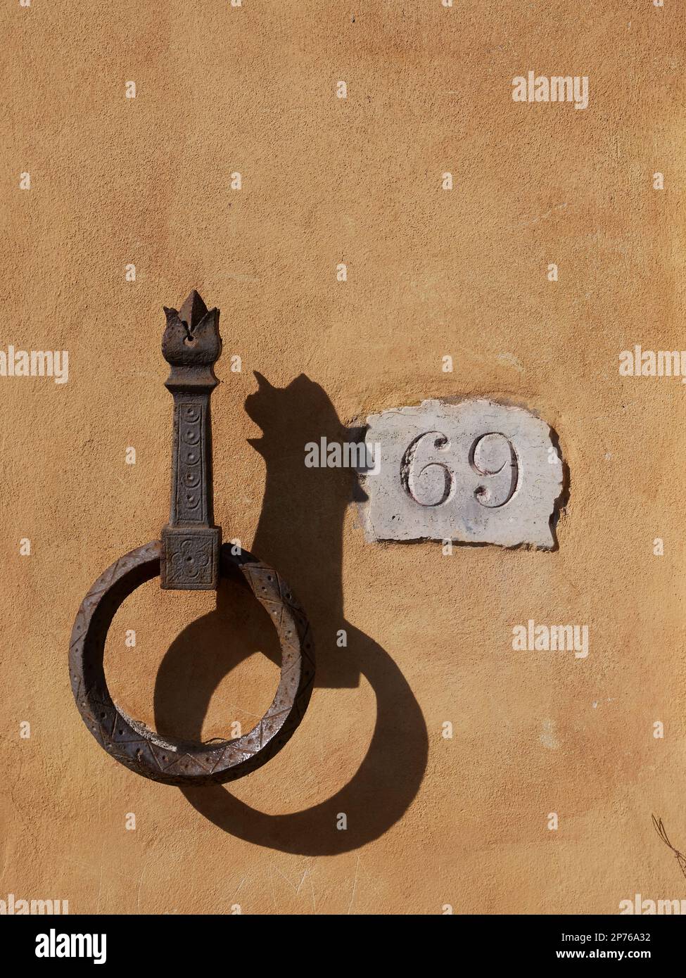 a metal ring for tethering a horse to on a wall with a number 69 plaque ...