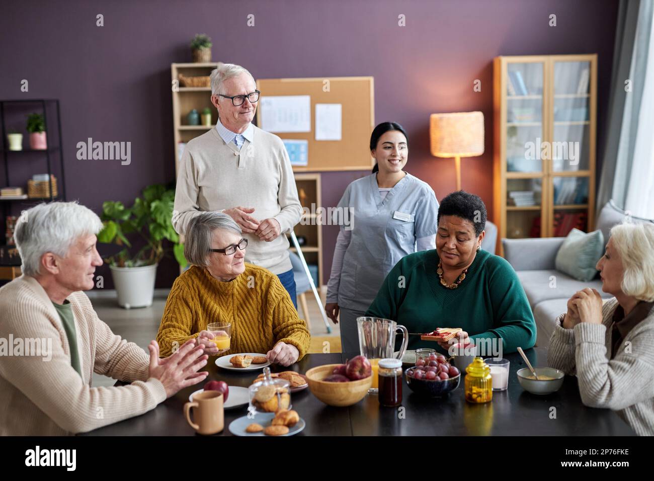 Breakfast scene in retirement home with group of smiling senior people ...