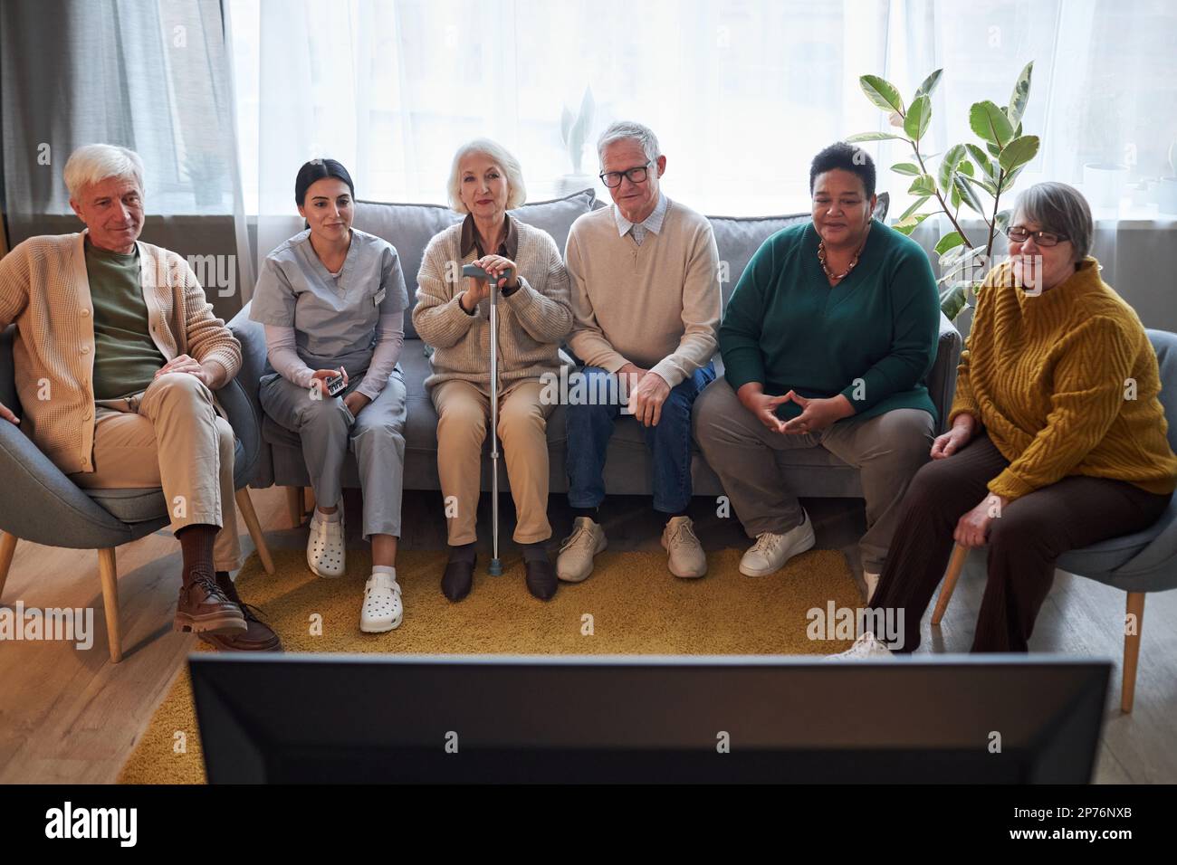 Full length view at group of elderly people watching TV in retirement ...