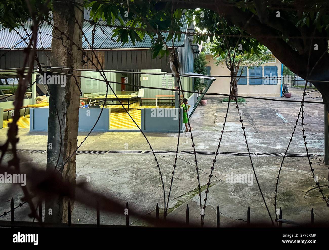A view past razor wire of a young boy in the compound of the museum at ...