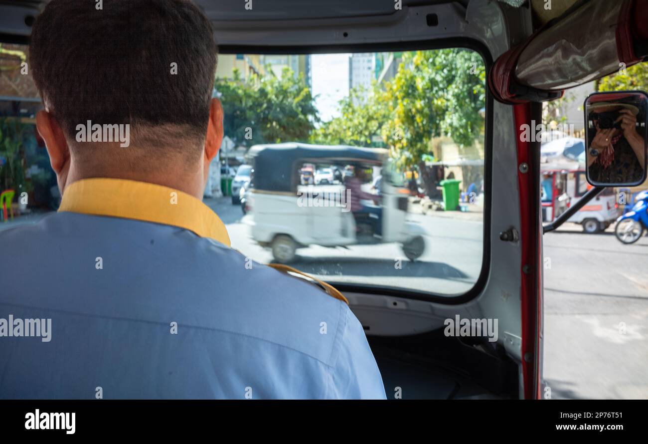 A tuk tuk, or auto rickshaw, driver approaches a traffic intersection ...