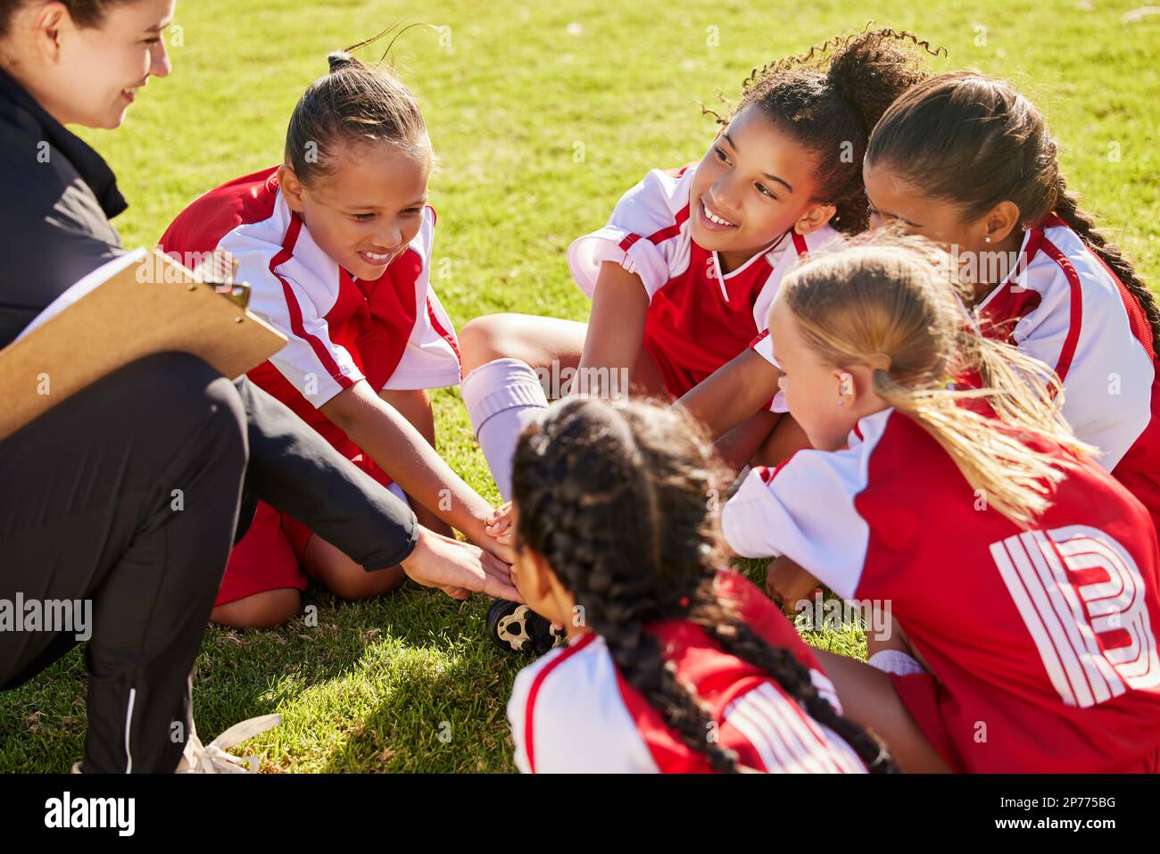 Girl soccer group, sitting and planning with coach on field with smile ...