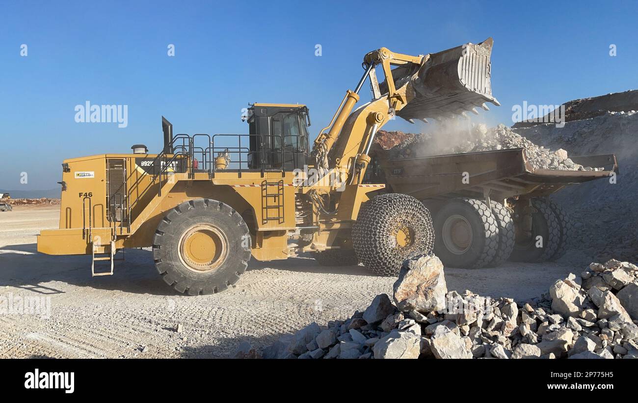 Wheel Loader loading soil on trucks, working at a huge mining site ...