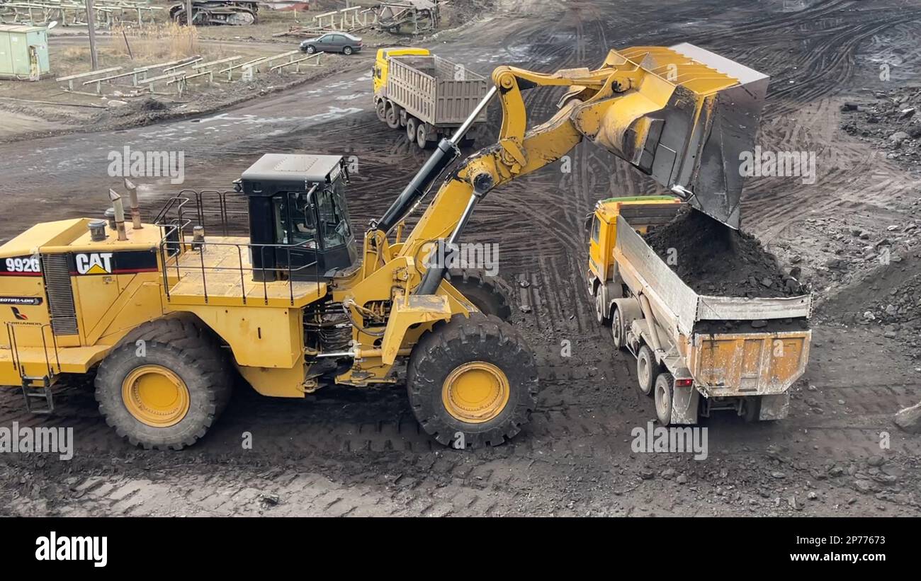 Wheel Loader loading soil on trucks, working at a huge mining site ...