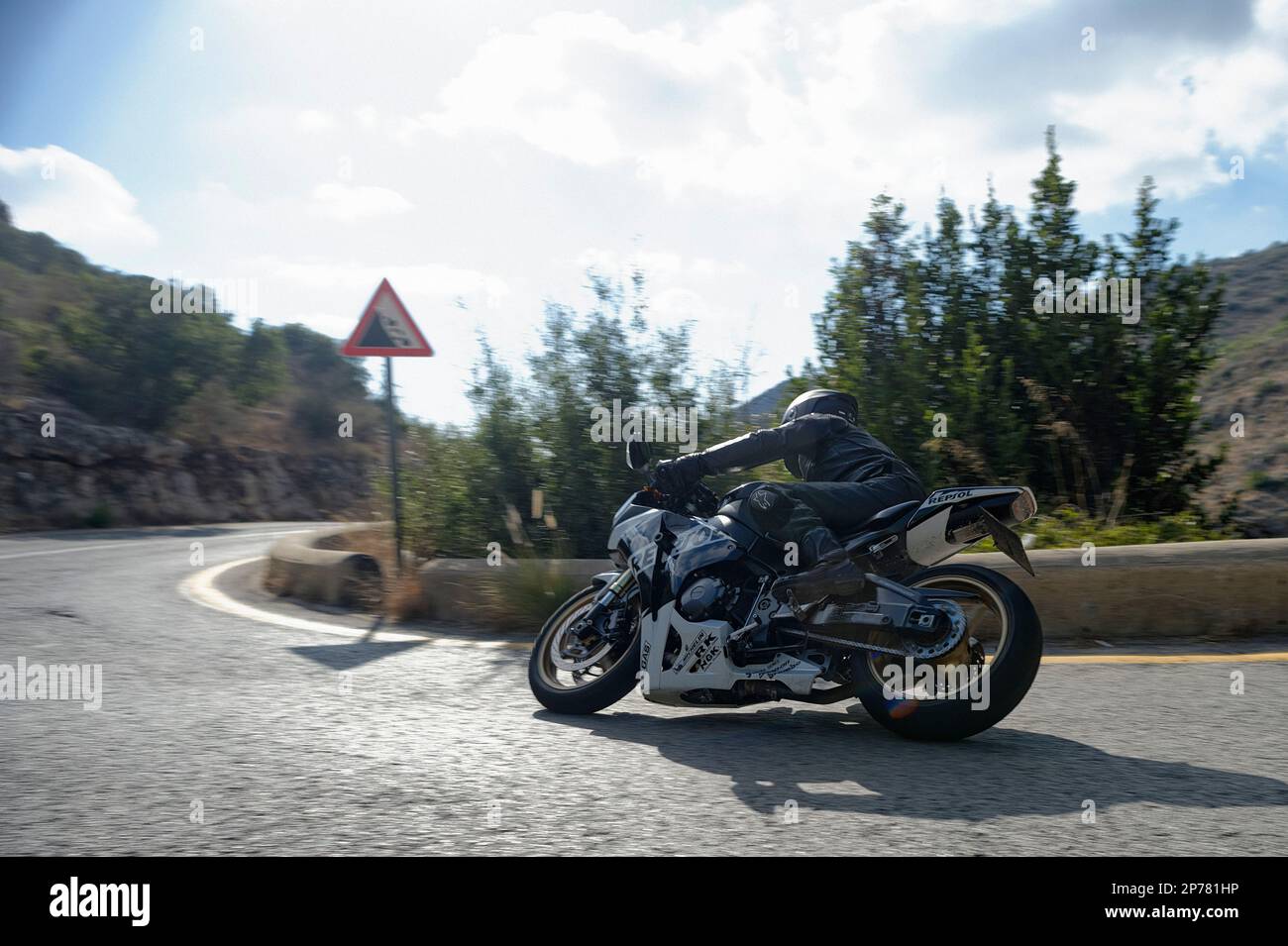 Motorcycle rider leaning into a turn on a twisty road with falling ...